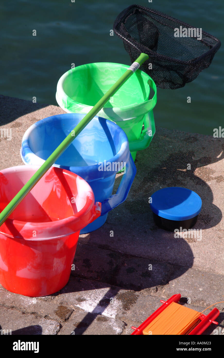 A row of colourful children's buckets and fishing net at the seaside ...