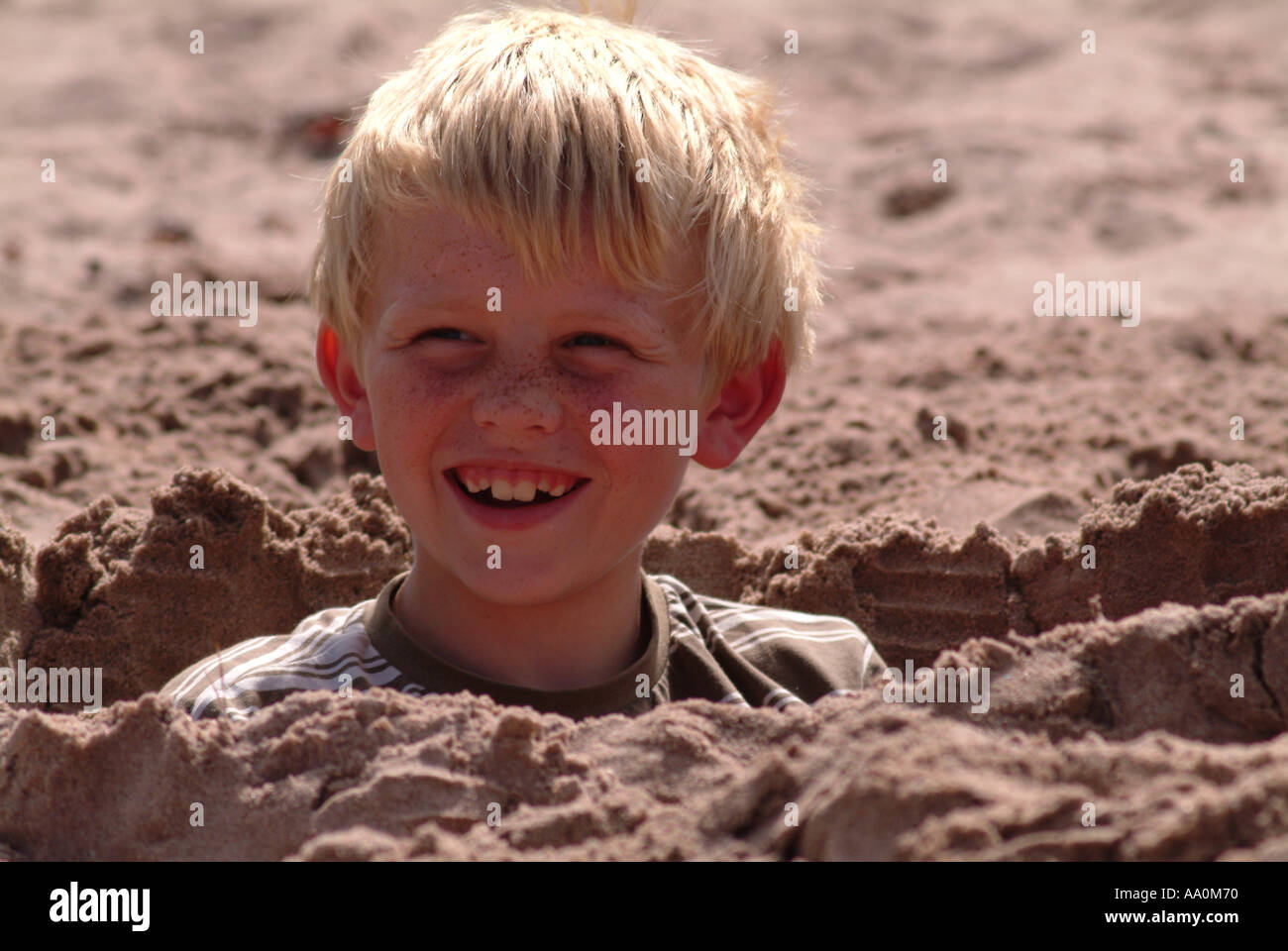 Little boy sitting inside a hole on the beach Stock Photo - Alamy