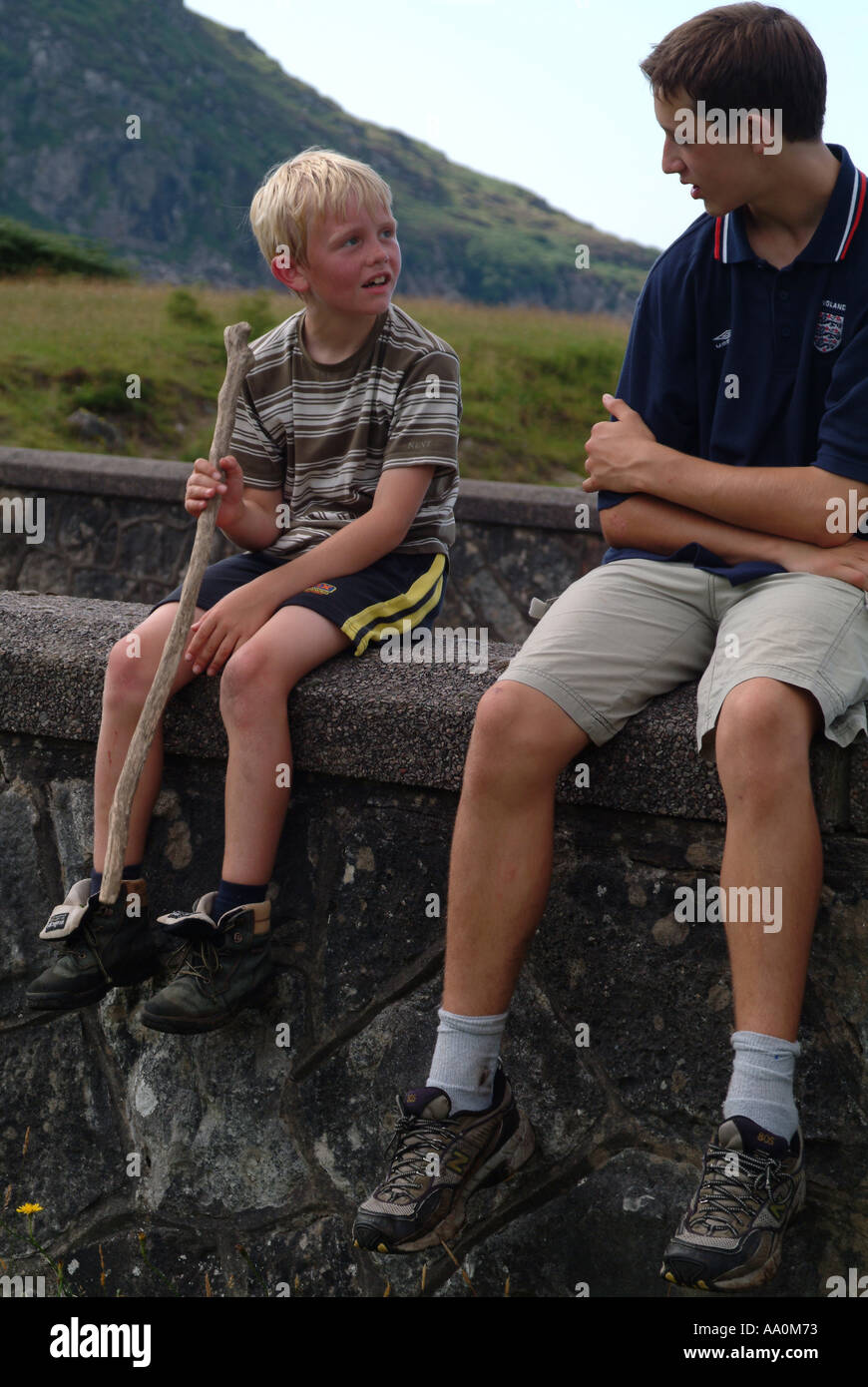 Two boys sitting on a stone wall in the countryside Stock Photo - Alamy