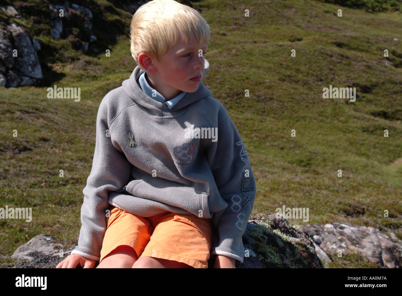 Little boy sitting on a rock in the countryside Stock Photo - Alamy