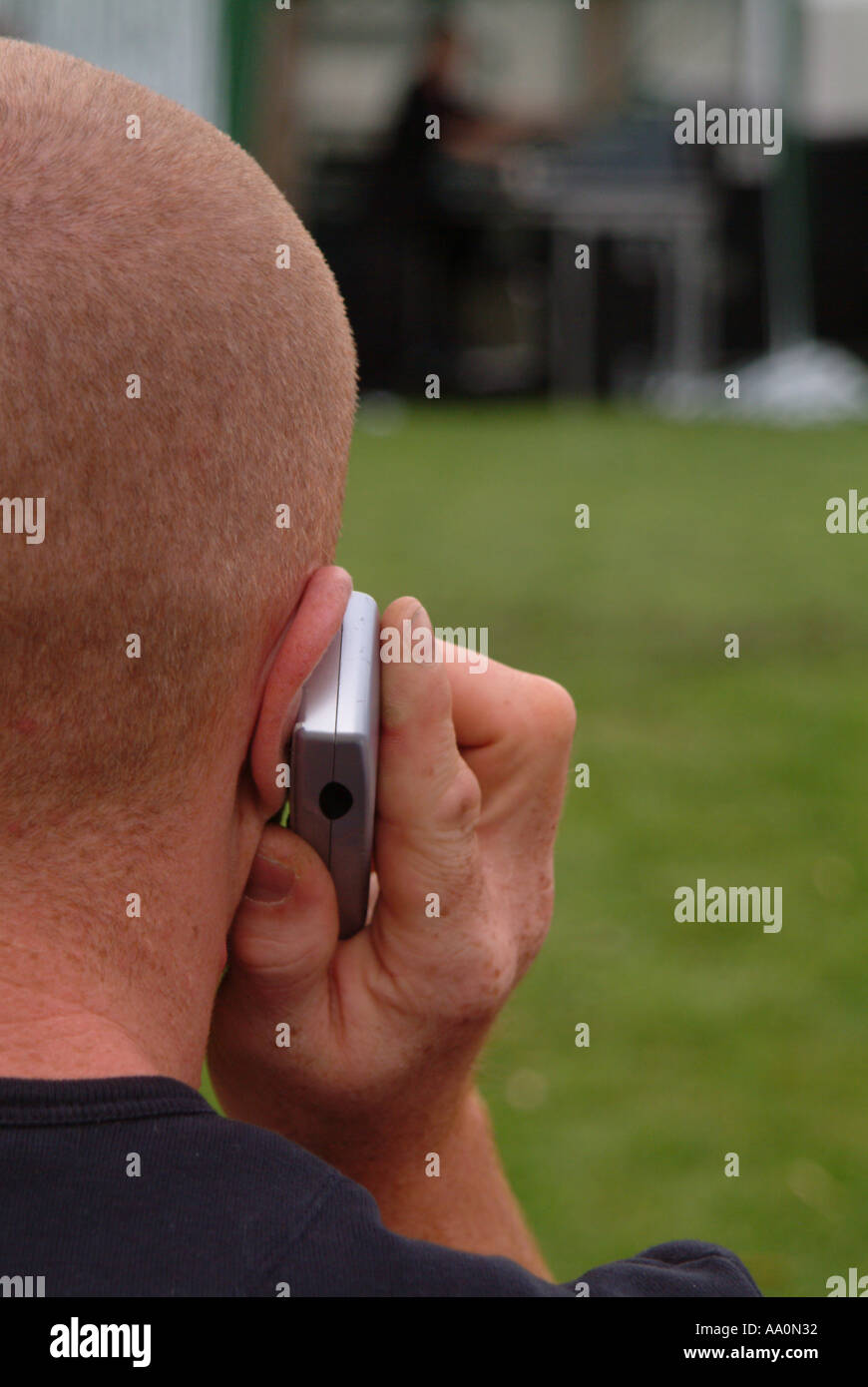 Rear view of a man with a shaved head using a mobile phone Stock Photo ...