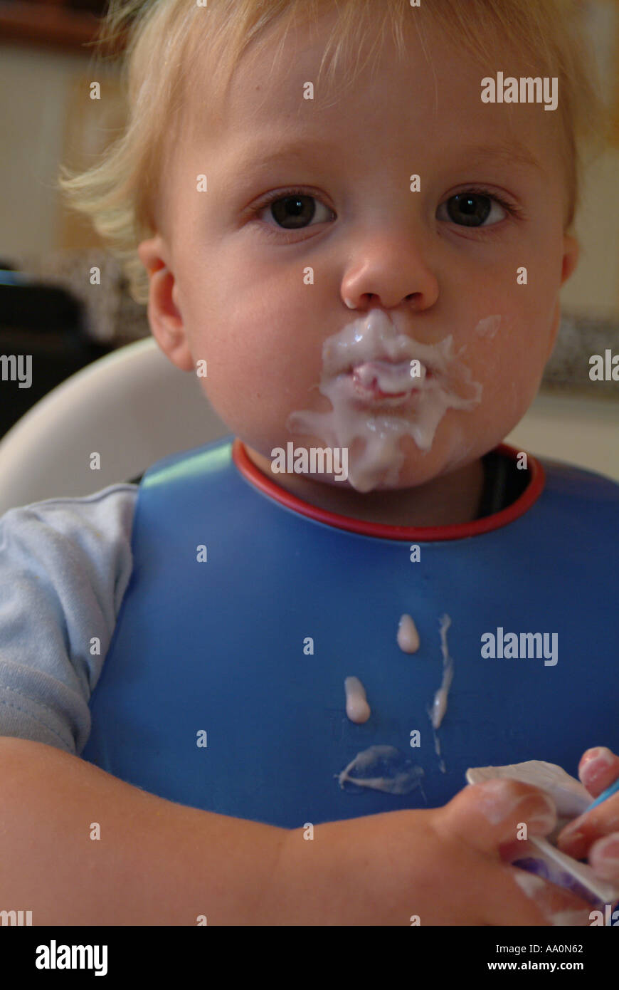 Baby eating a yoghurt with a messy face Stock Photo - Alamy