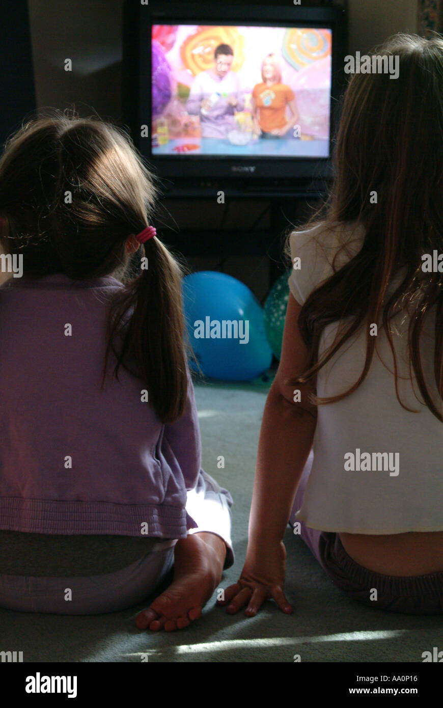 Rear view of two young girls watching television Stock Photo - Alamy