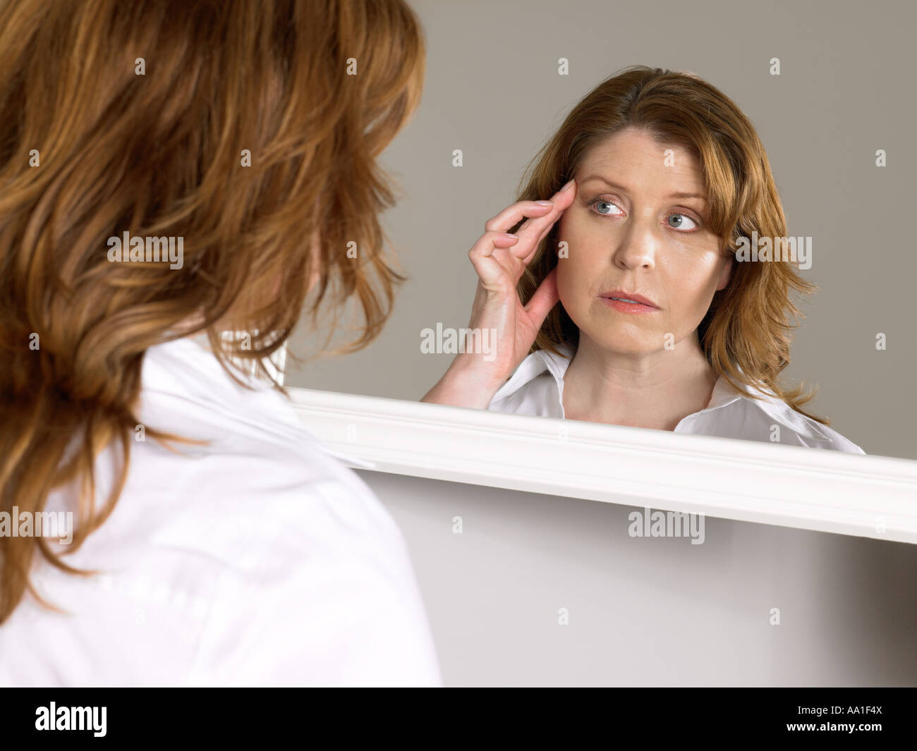Woman looking in mirror Stock Photo - Alamy