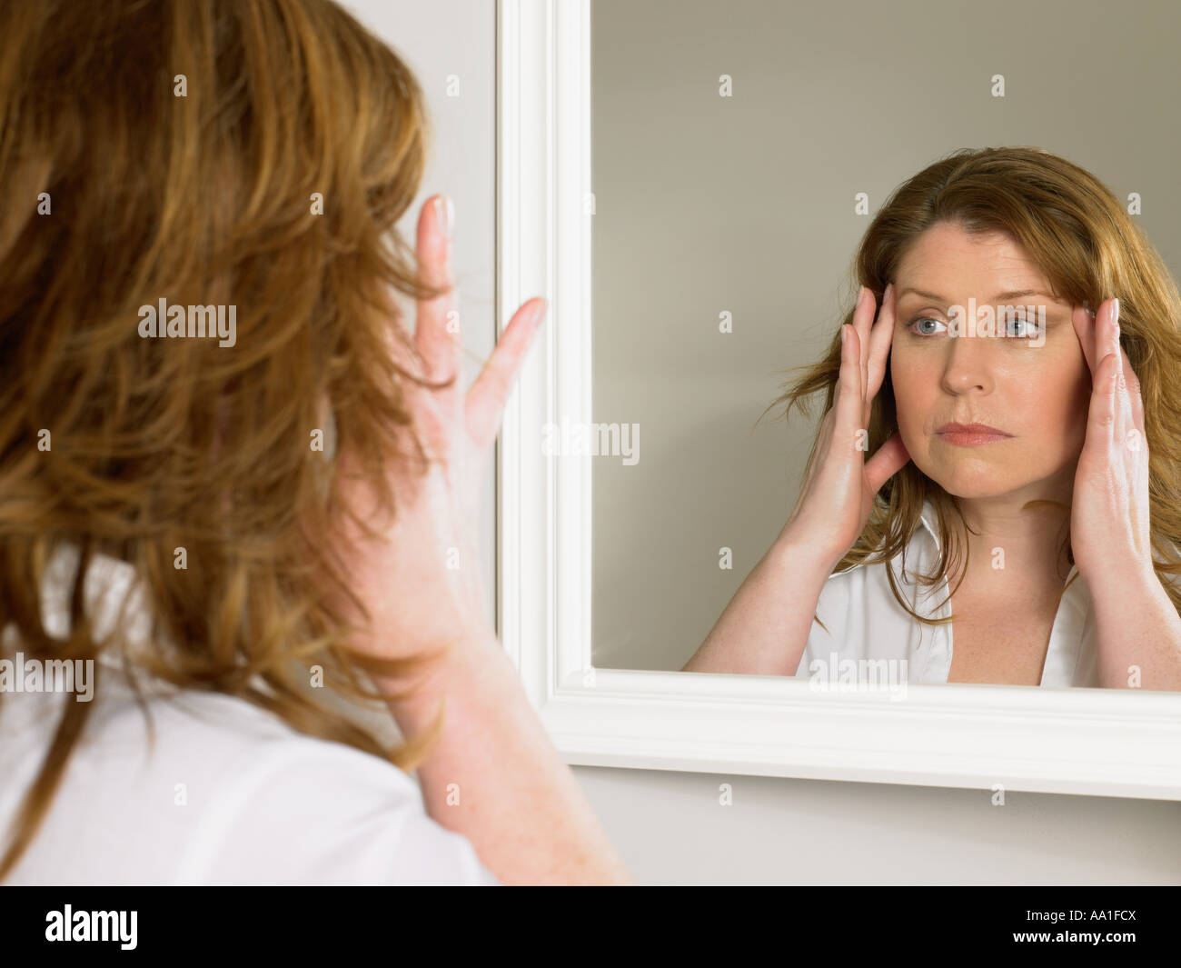 Woman looking in mirror Stock Photo - Alamy