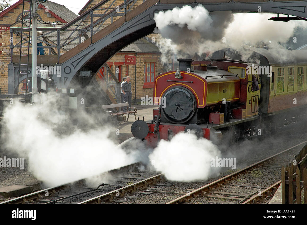A preserved steam locomotive and train pulling away from a station ...