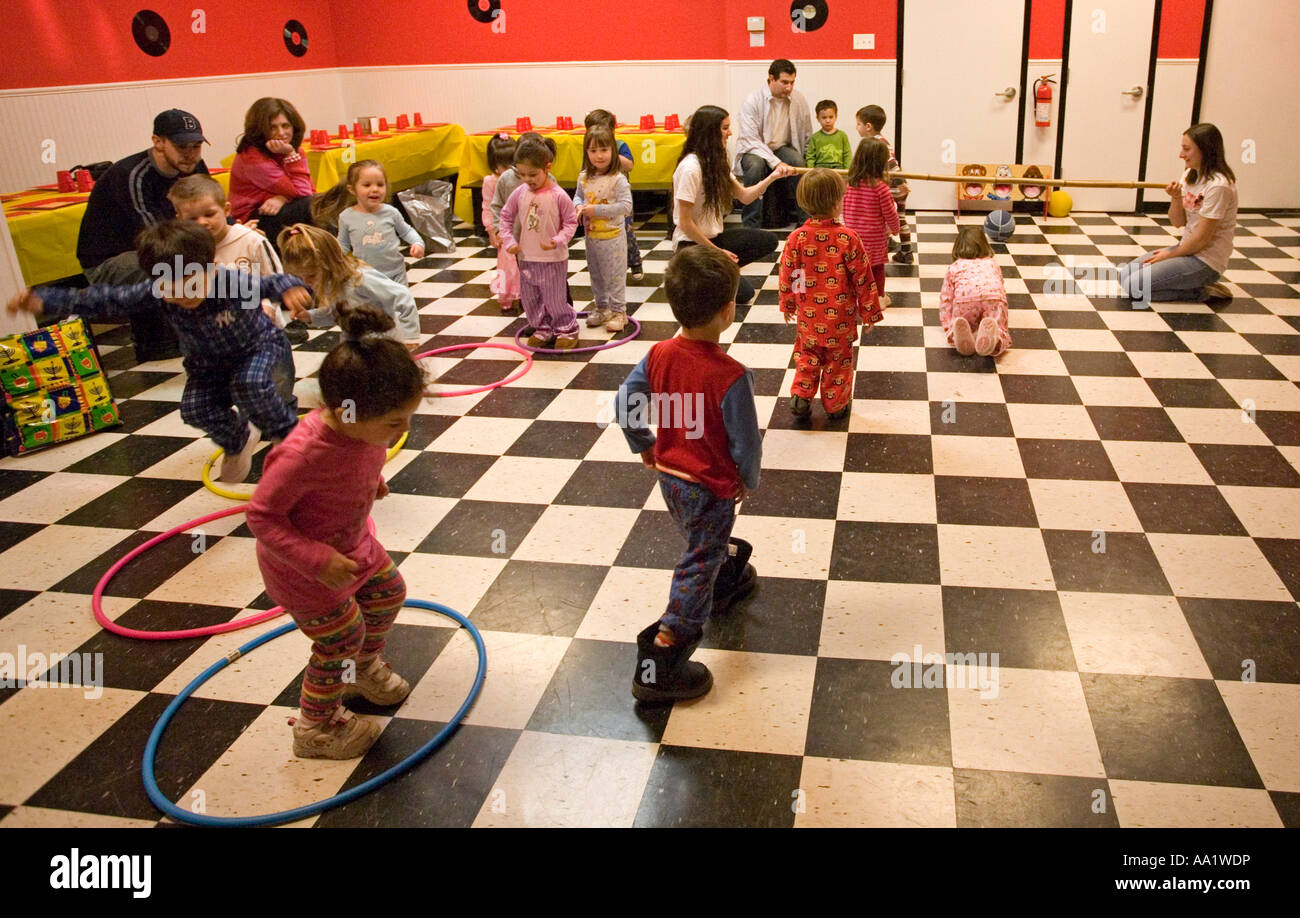 Three year old children walk through hula hoops to do limbo at birthday ...