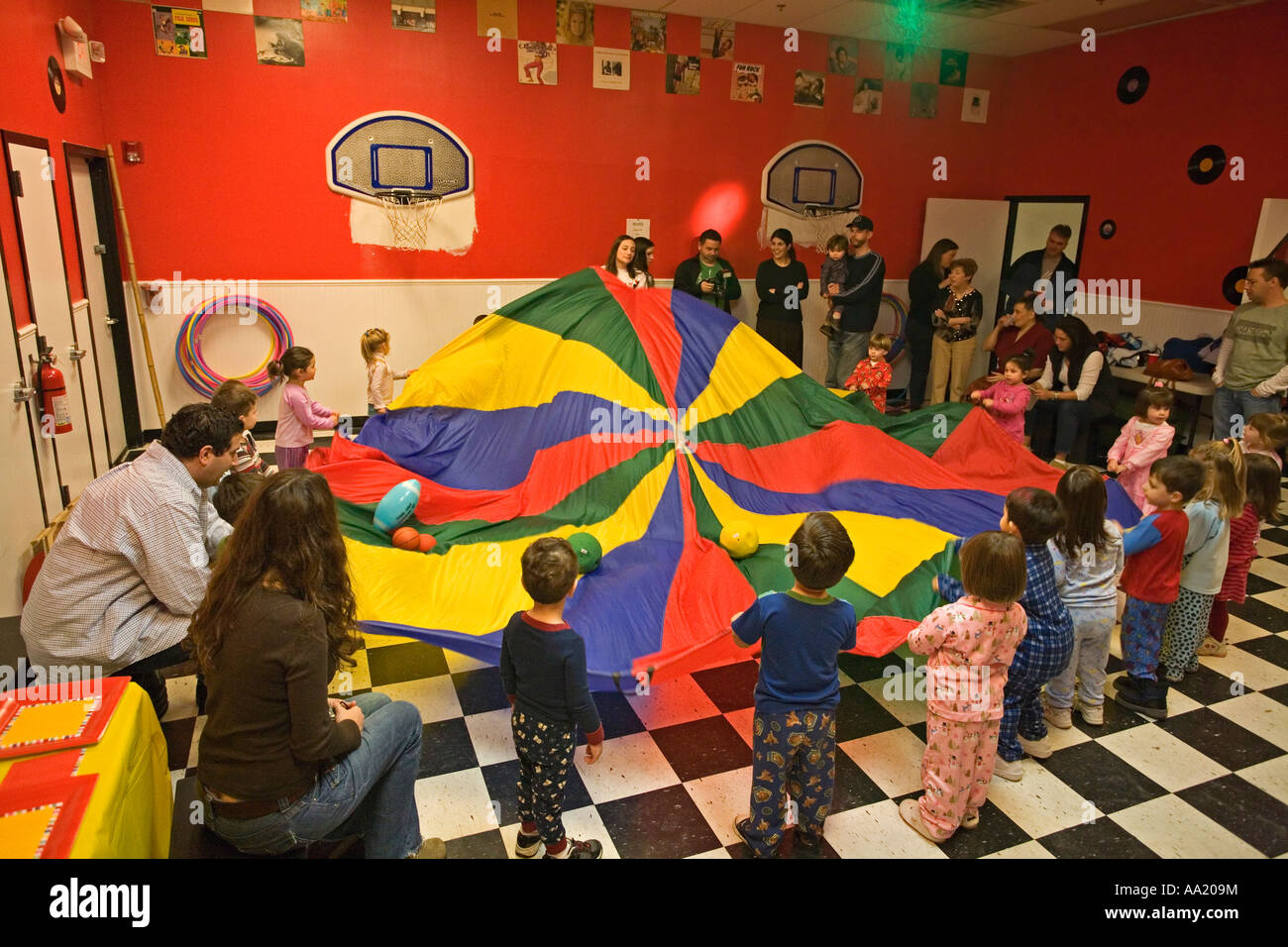 Three year old children flap colorful parachute up and down at birthday ...