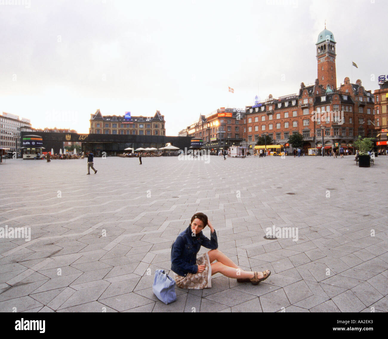 Denmark, Copenhagen, young woman sitting on ground, side view Stock ...
