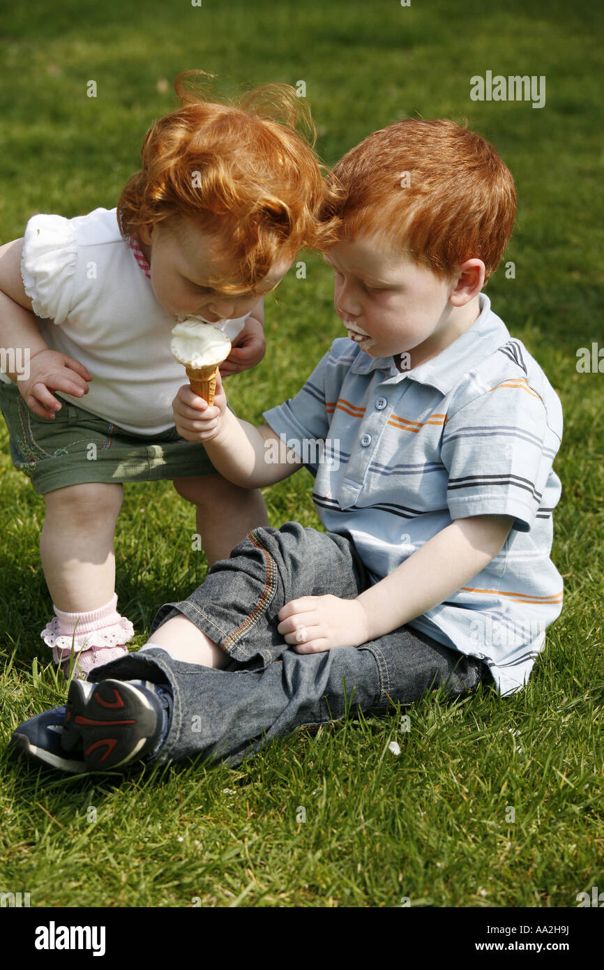 Two children sharing an ice cream in a park Stock Photo - Alamy