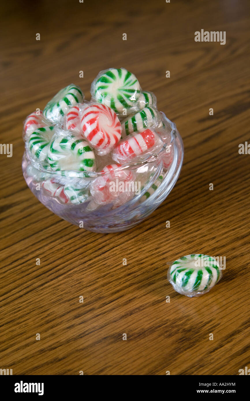 A bowl of red and green striped mints with one mint on the table Stock ...