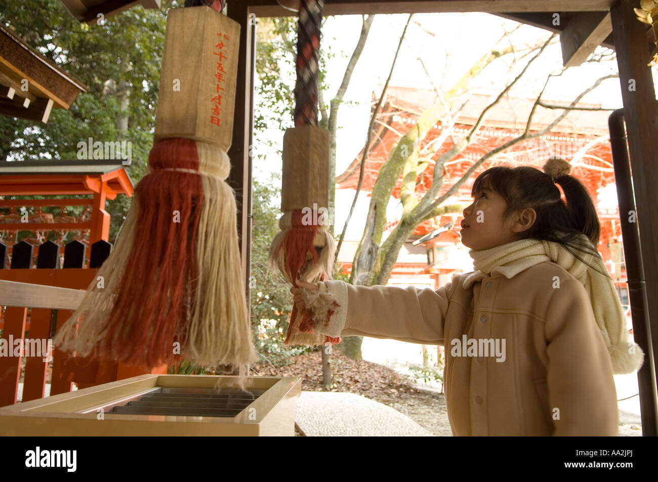 Girl shaking bell at shrine Stock Photo - Alamy