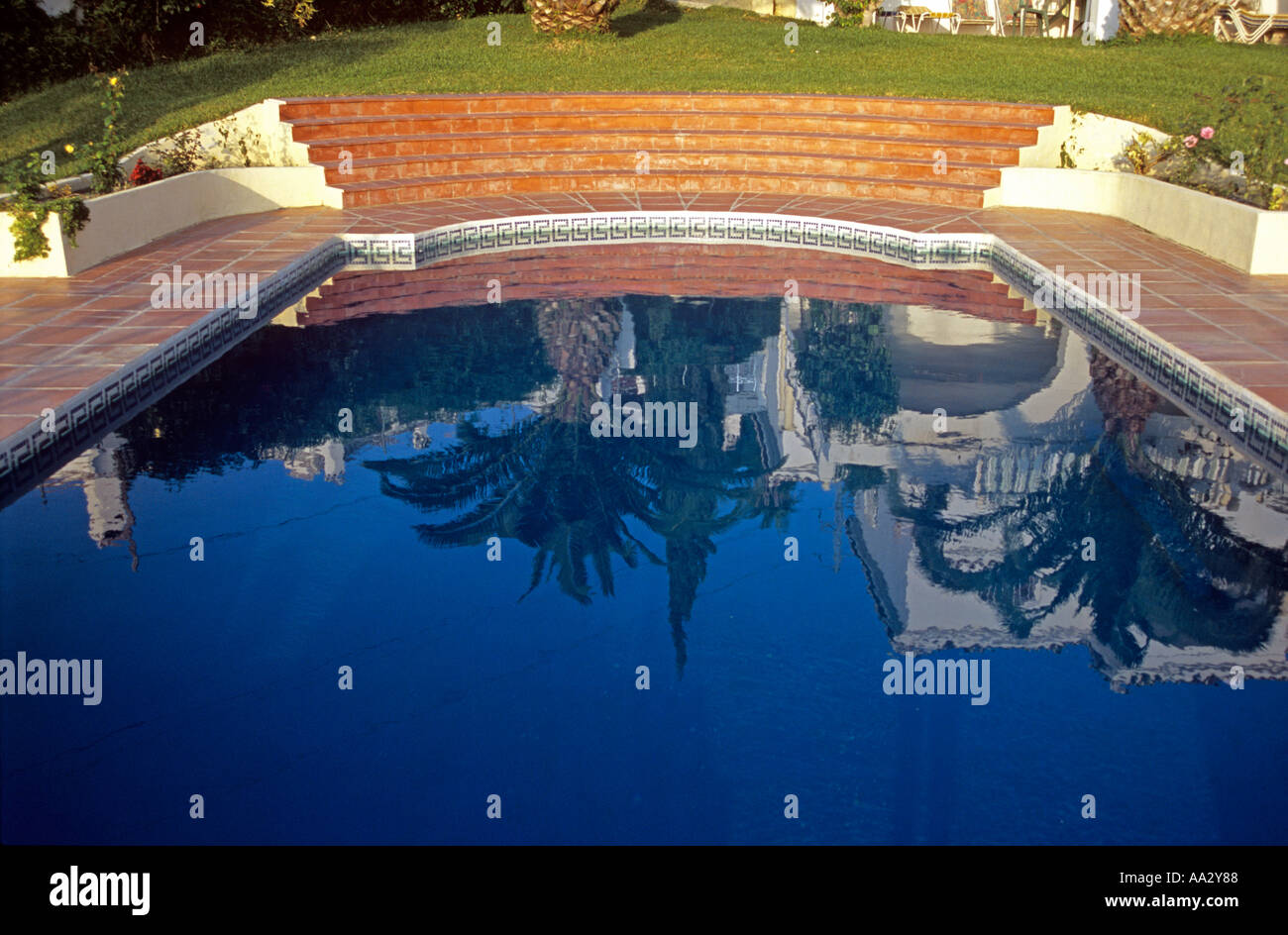 swimming pool with terracotta tiles surround and reflection of white ...