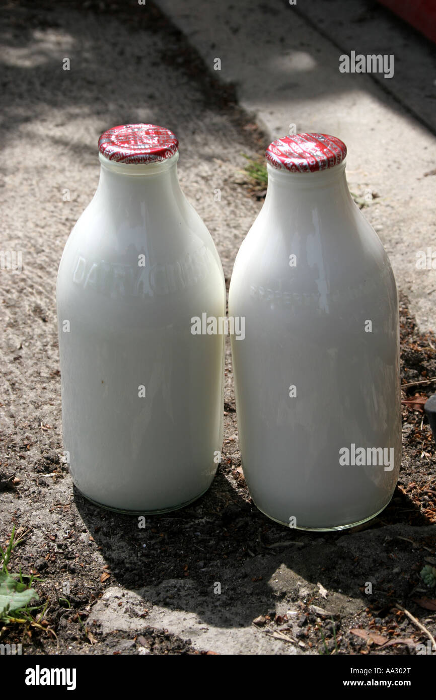 Two red topped full milk bottles outside a front door Stock Photo - Alamy
