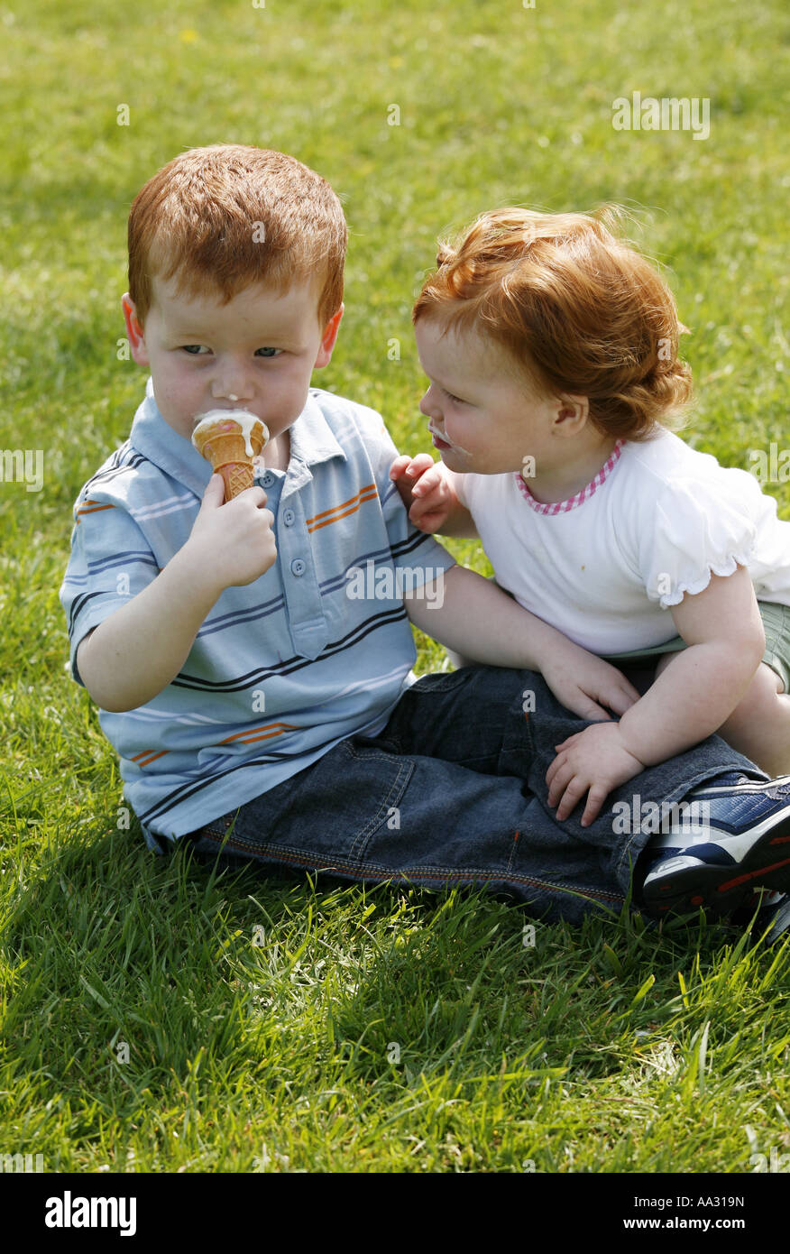 Two children sharing an ice cream in a park Stock Photo - Alamy