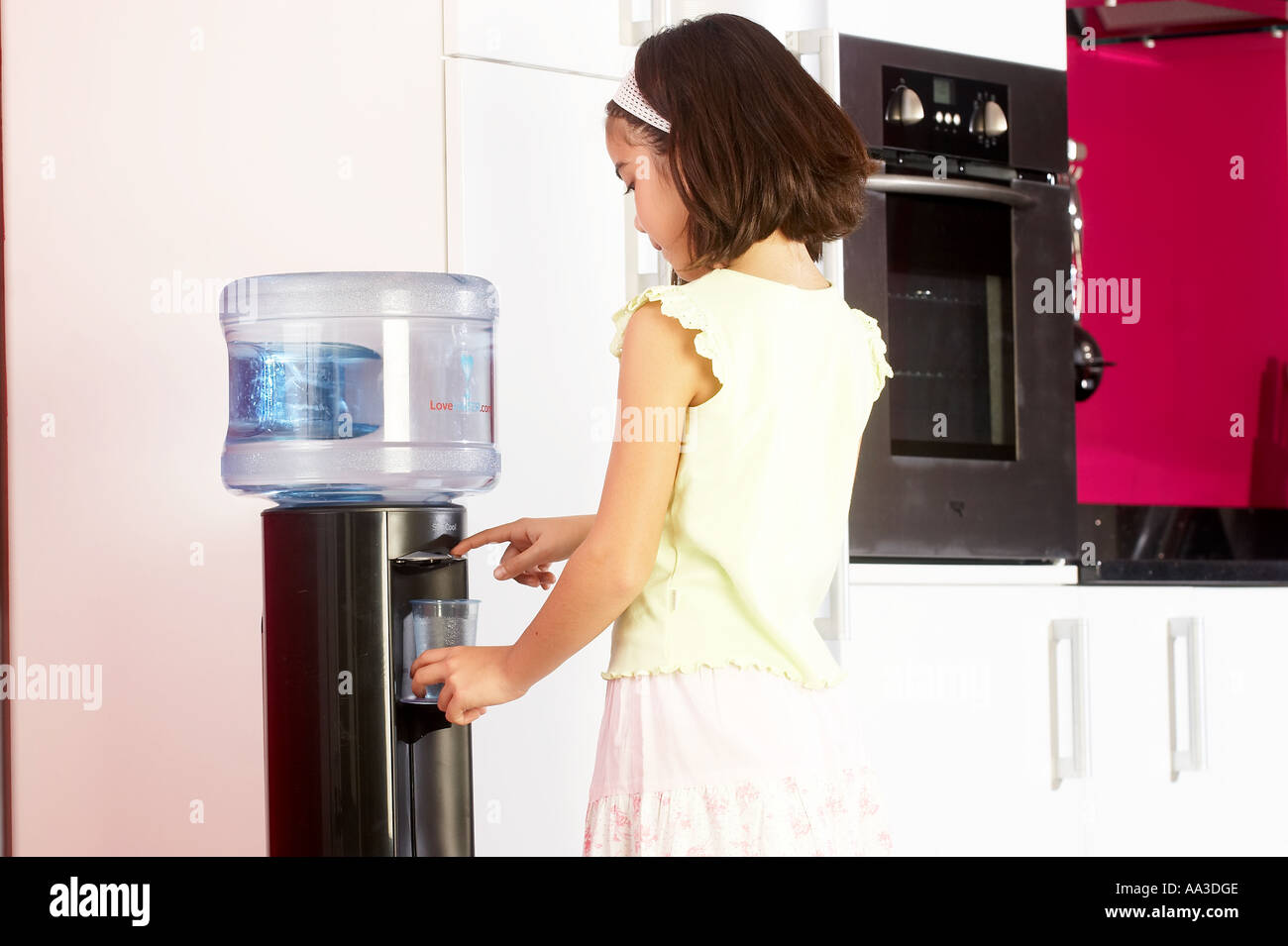 Child getting drink from a water cooler in the kitchen Stock Photo - Alamy