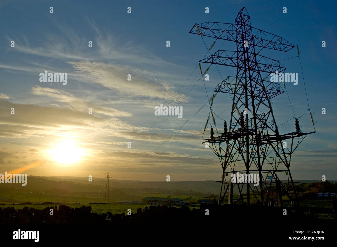 Sun setting behind electricity pylon Stock Photo - Alamy