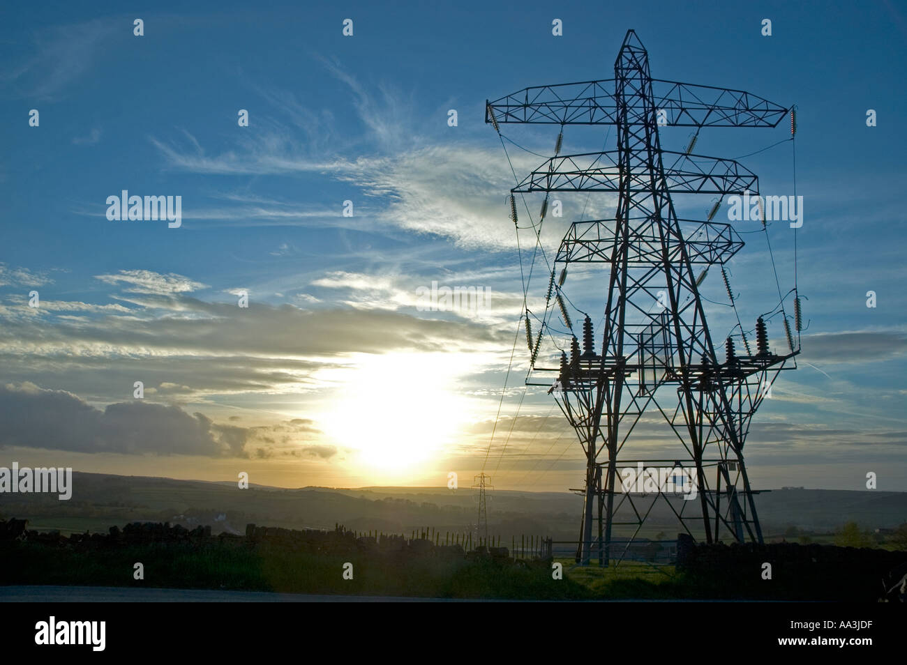 Sun setting behind electricity pylon Stock Photo - Alamy