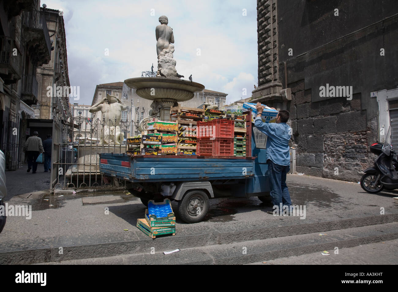Man loading boxes of fruit and vegetables onto Ape transporter at ...