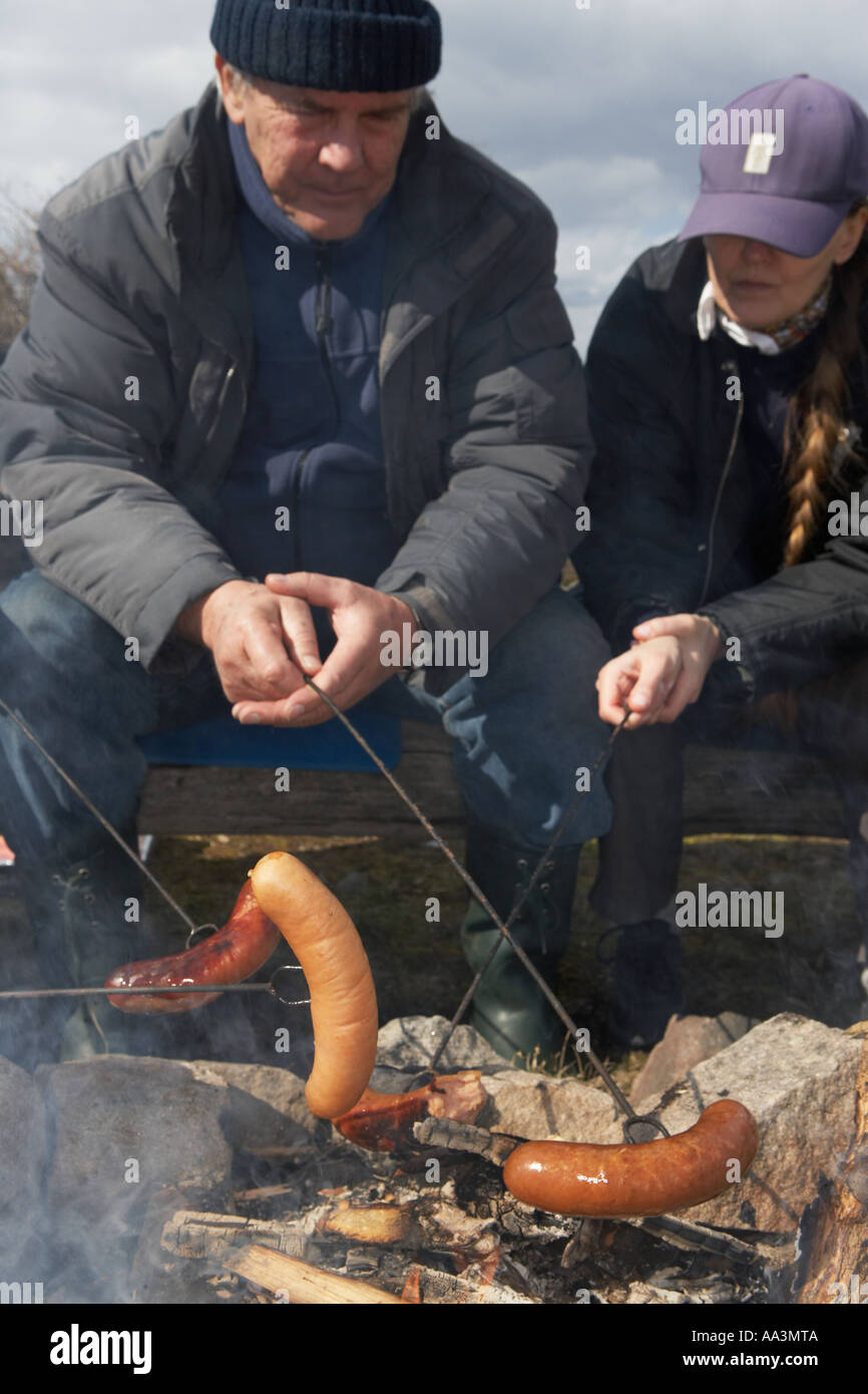 Two generation roasting hotdogs over an open fire Stock Photo - Alamy