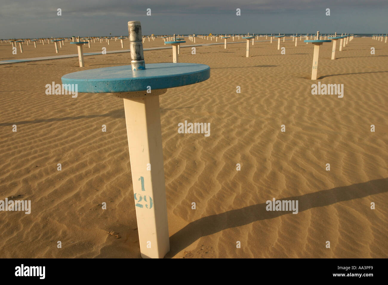 Parosol umbrella bases forming a perspective pattern across the beach ...