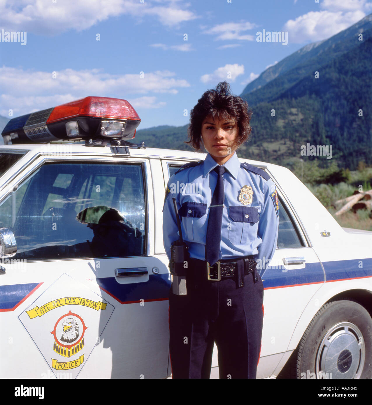Tribal policewoman standing next to police car Lillooet, British ...