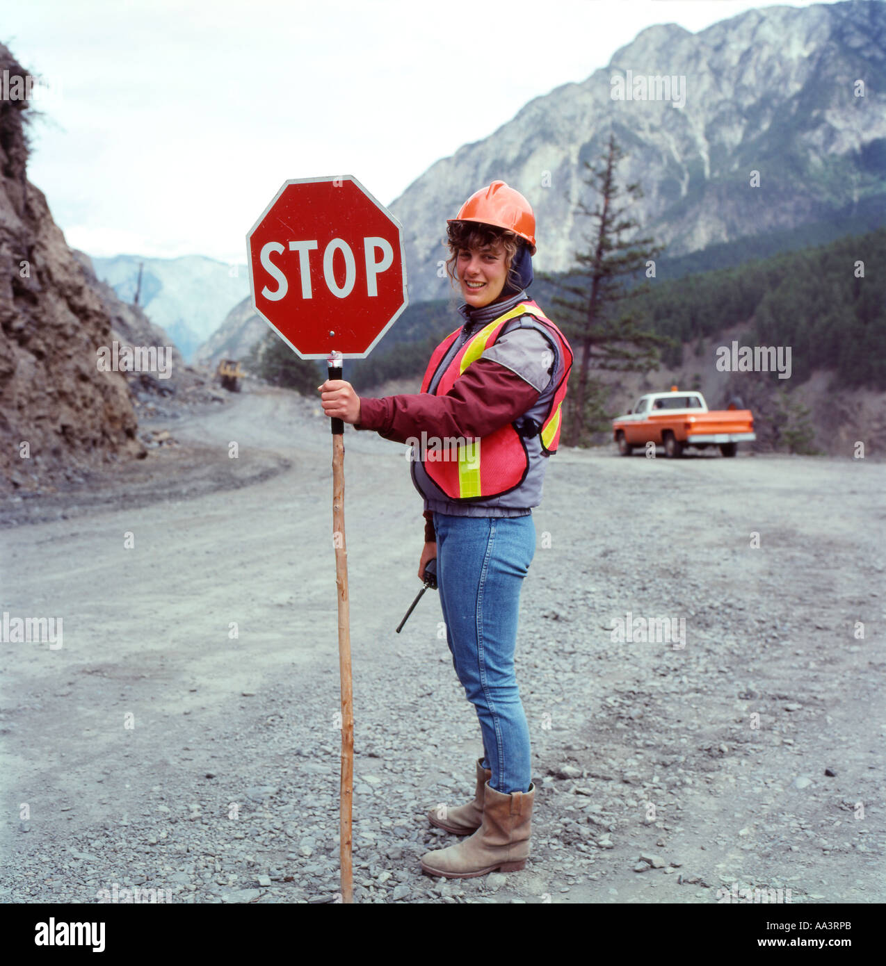 A female traffic controller holding a stop sign on a road construction ...