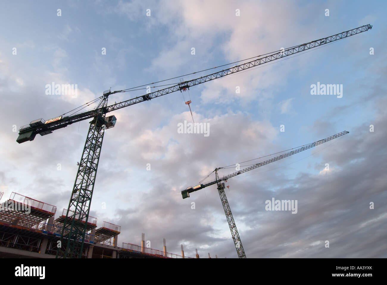 Two cranes at a construction site late evening taken from a low angle ...
