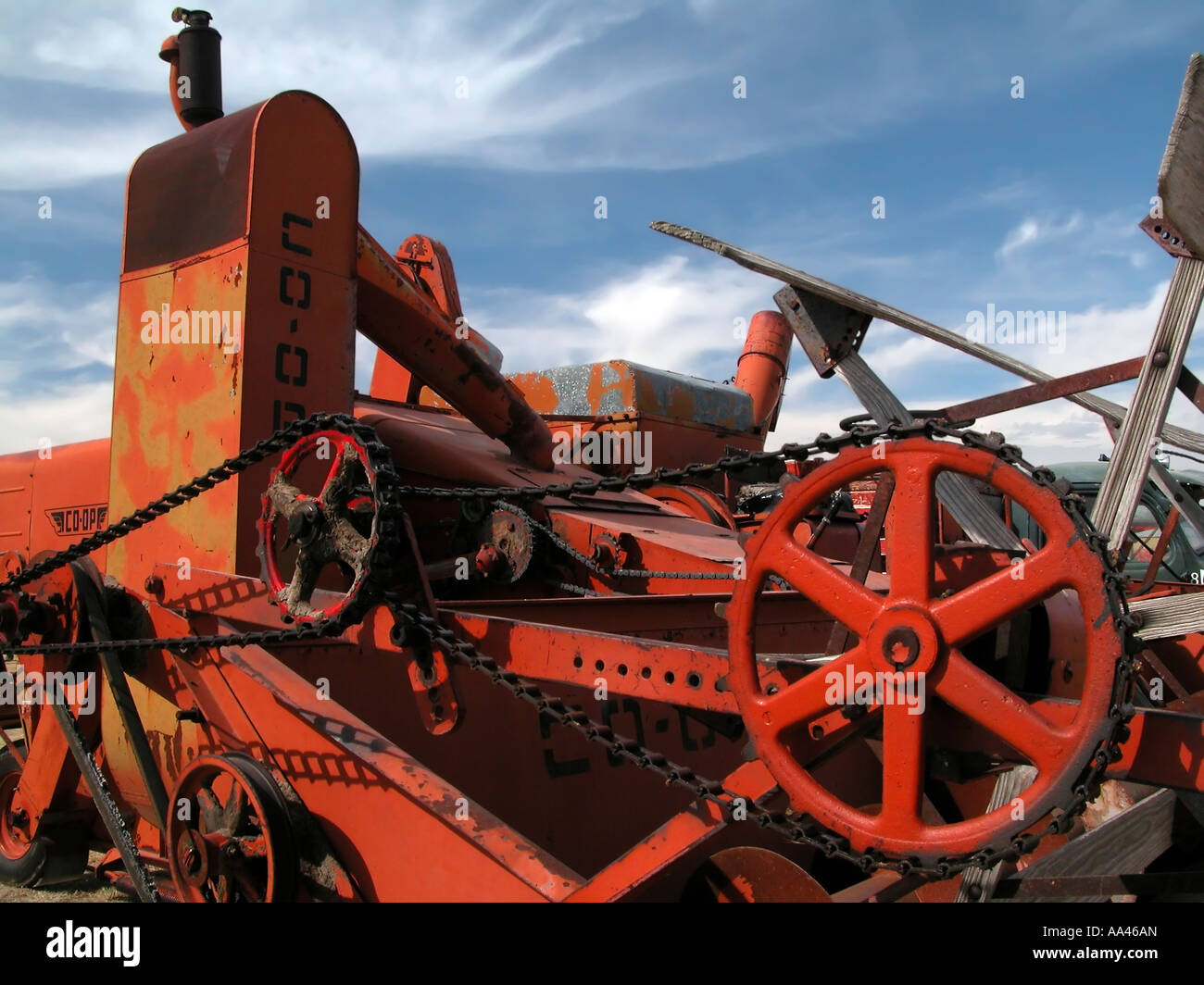 Orange CO OP Combine Thresher with exposed chains and wooden paddles at ...