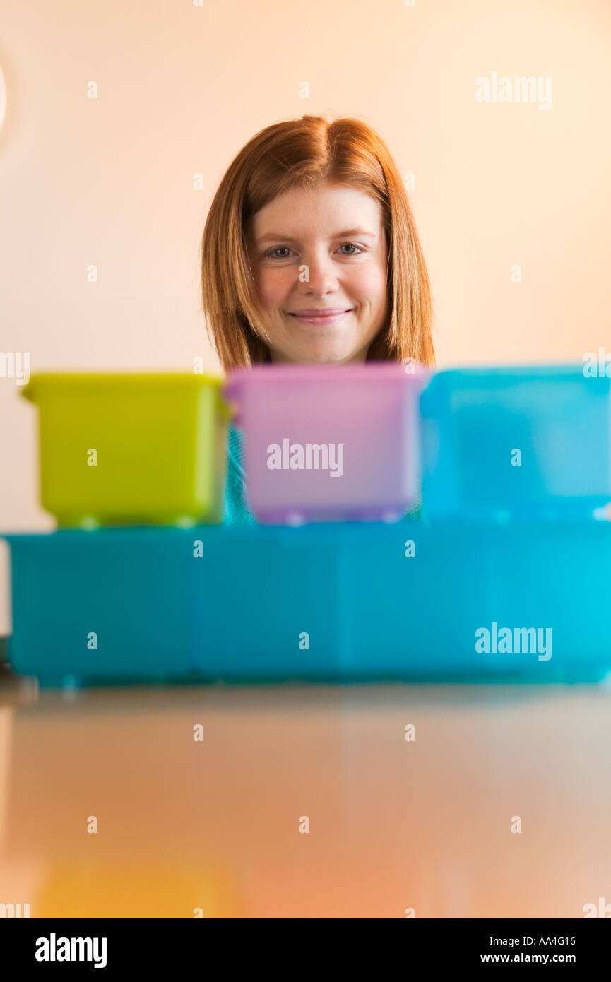 Woman sitting behind colourful storage boxes Stock Photo - Alamy