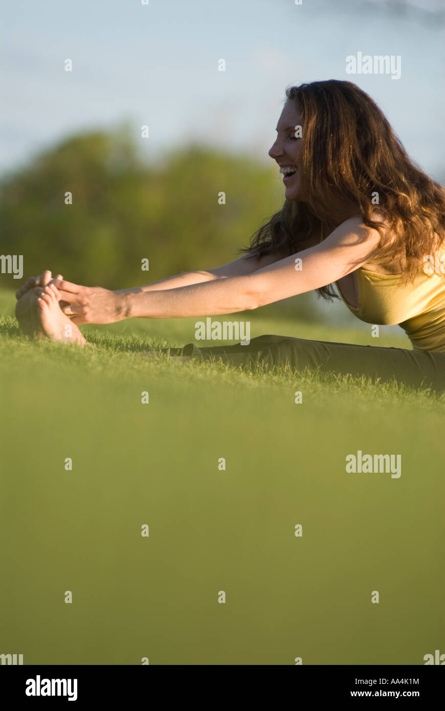 Young woman sitting in the grass stretching her legs Stock Photo - Alamy