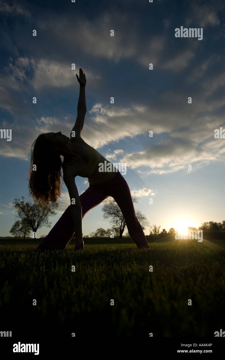 Young woman doing yoga at sunset- triangle pose Stock Photo - Alamy