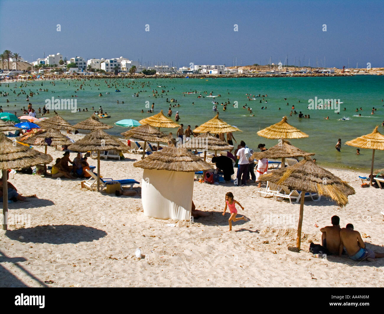 Thatch sunshades line beach holidaymakers cool off Monastir Beach ...