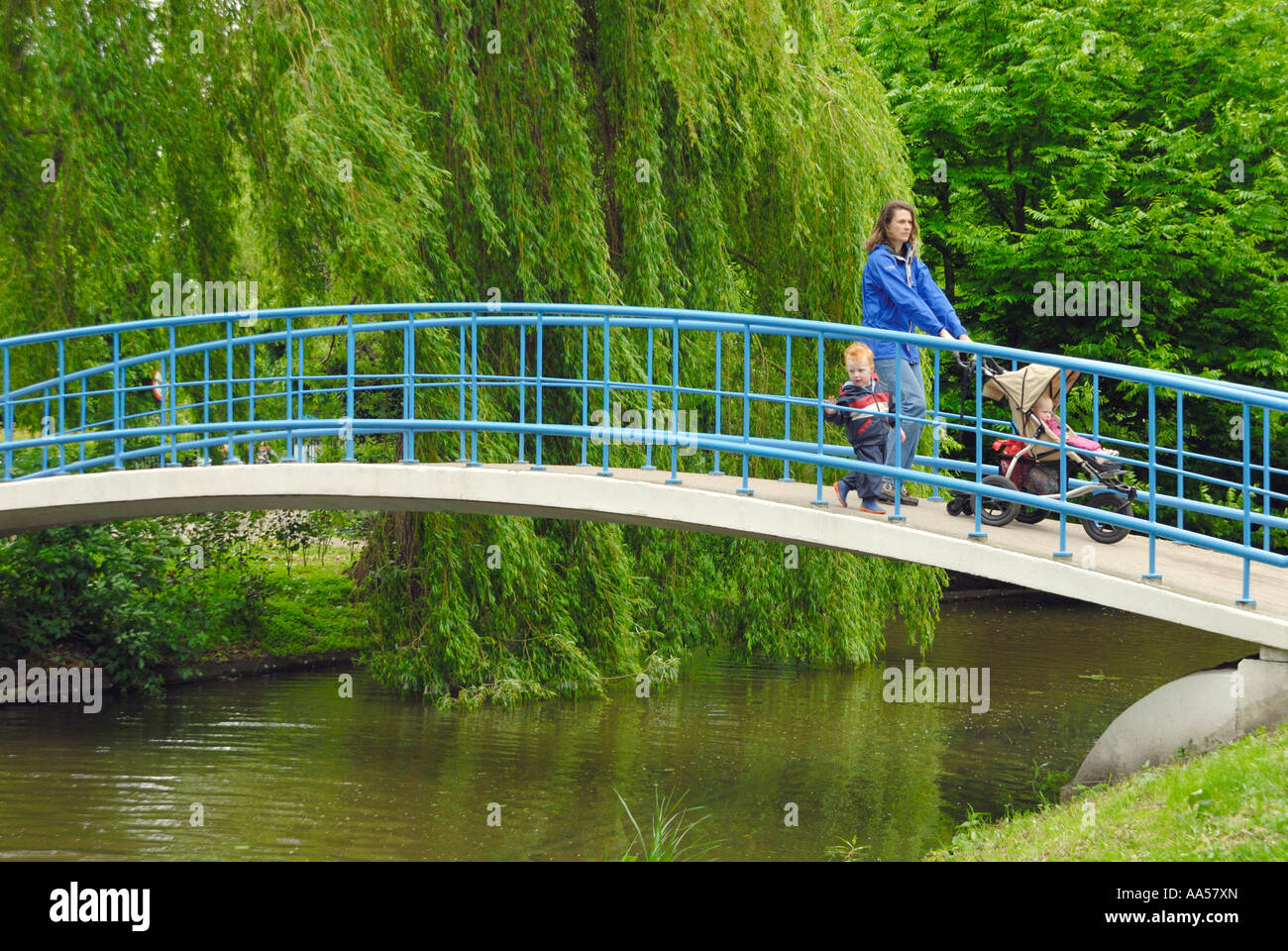 A woman with a baby and a child crossing a bridge in Vondelpark in ...