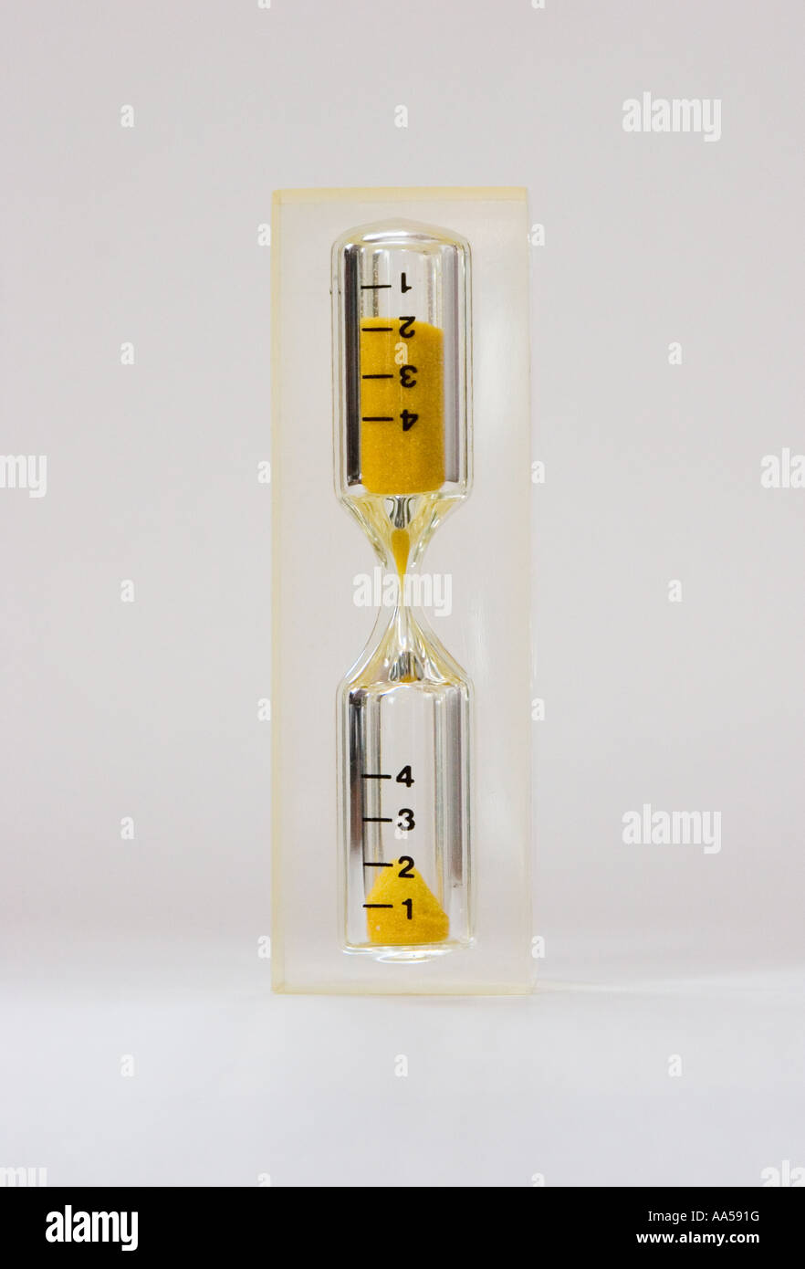Hour glass encased in a block of transparent perspex against a plain ...