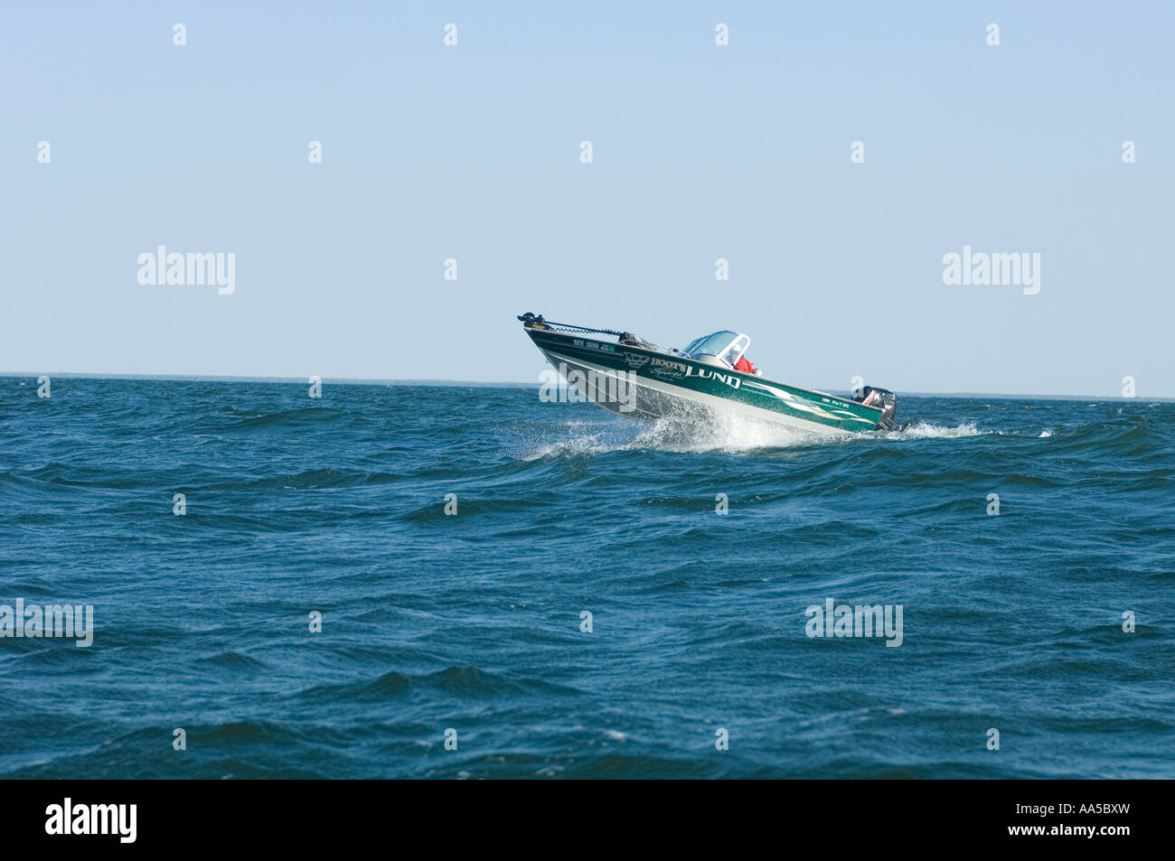 A LUND FISHING BOAT RIDES OVER WAVES WITH IT S BOW IN THE AIR LAKE ...