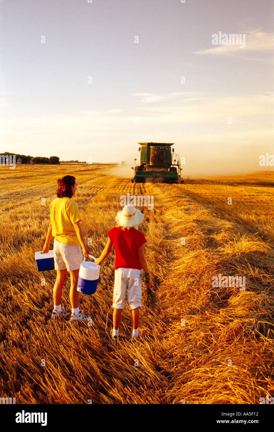 Two farm girls wait to deliver supper to their farmer father operating ...