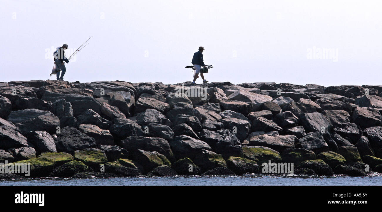 Surf fisherman hiking out on the jetty Stock Photo - Alamy