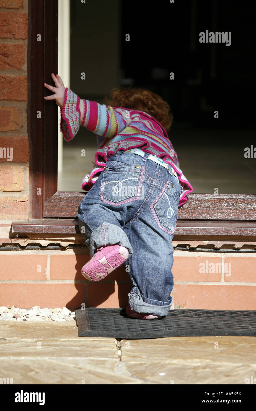 Baby girl climbing a step Stock Photo - Alamy
