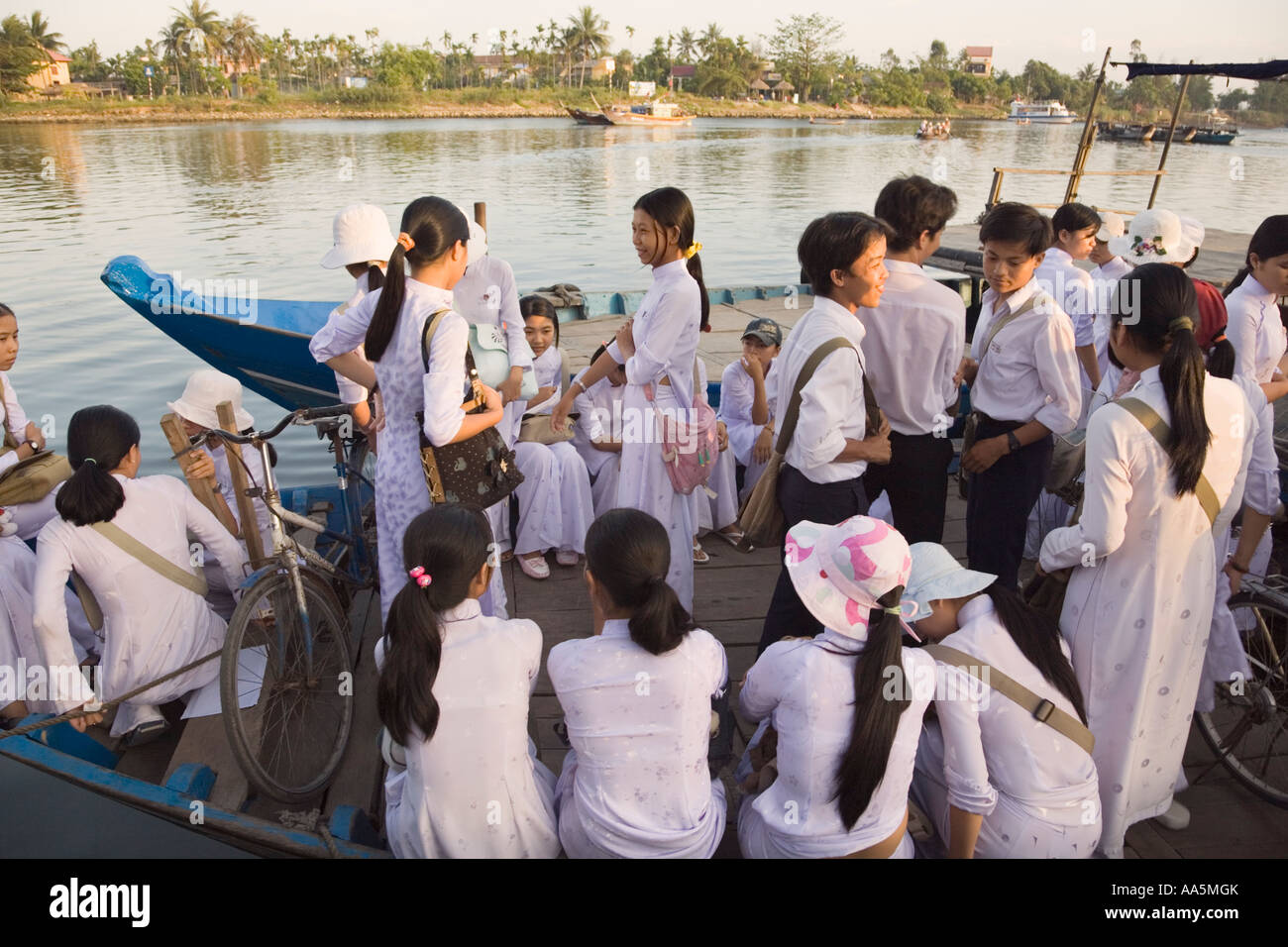 Hoi An, Vietnam. Students dressed in Ao Dai aboard a boat crossing the ...