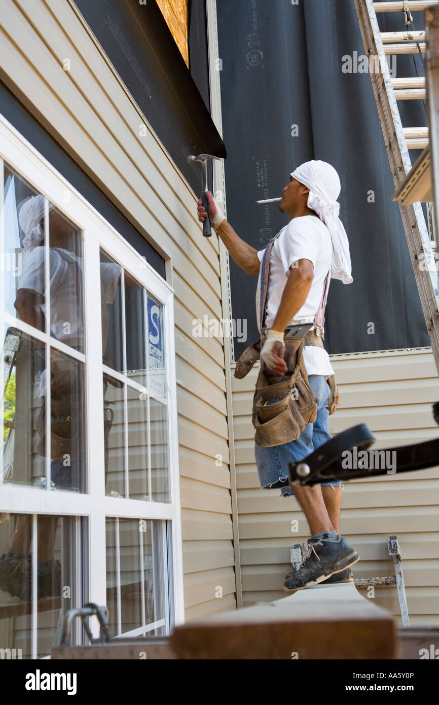 Immigrant Workers Installing vinyl Siding Stock Photo - Alamy