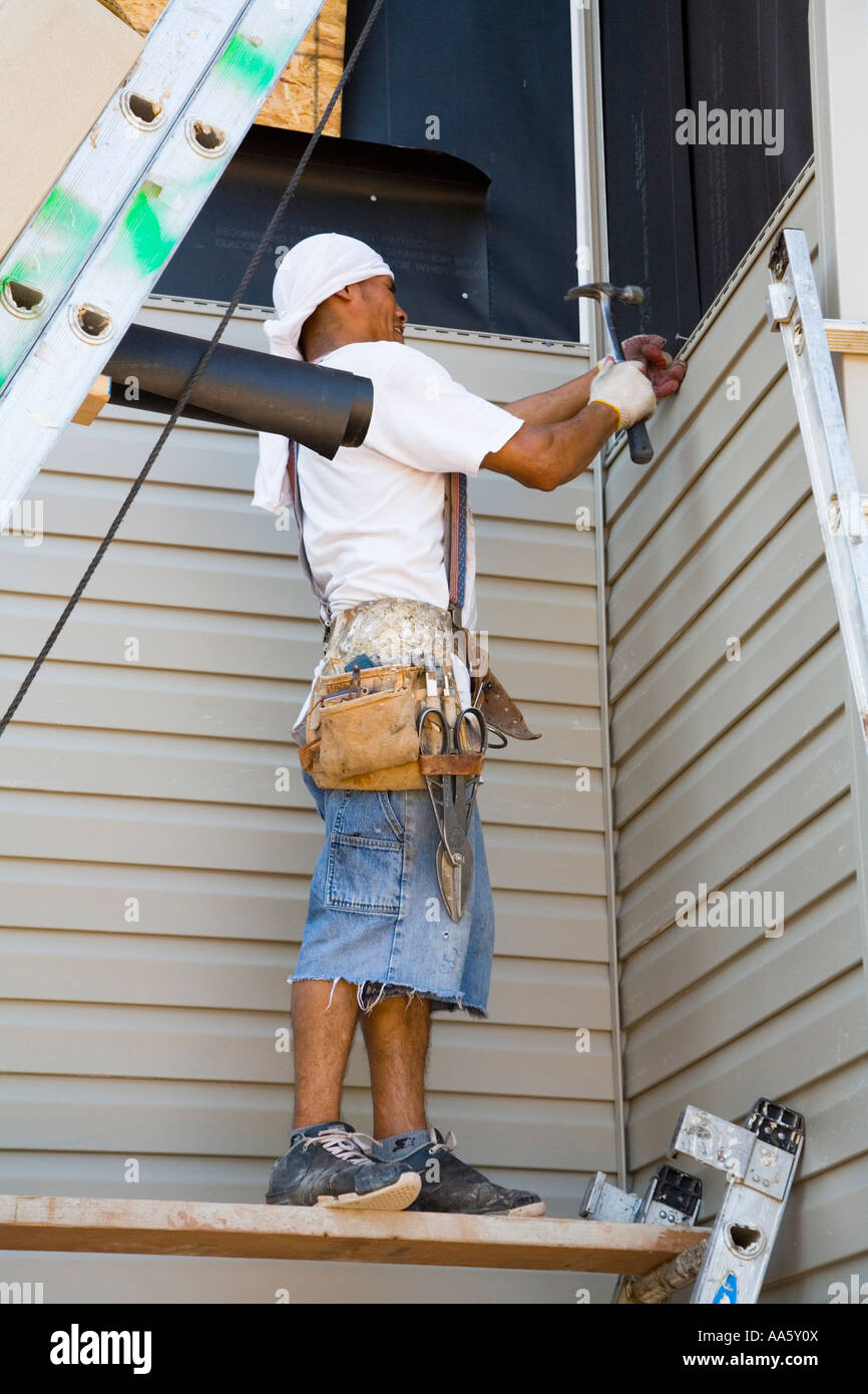 Immigrant Workers Installing vinyl Siding Stock Photo - Alamy