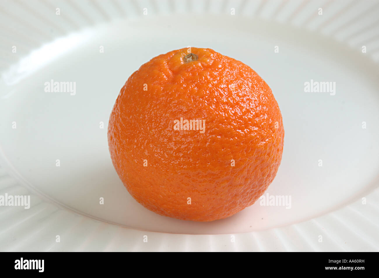 Orange fruit one whole in white plate Stock Photo - Alamy