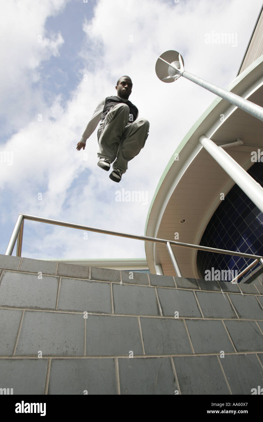 A parkour freerunning athlete vaults jumps over a rail in the city ...