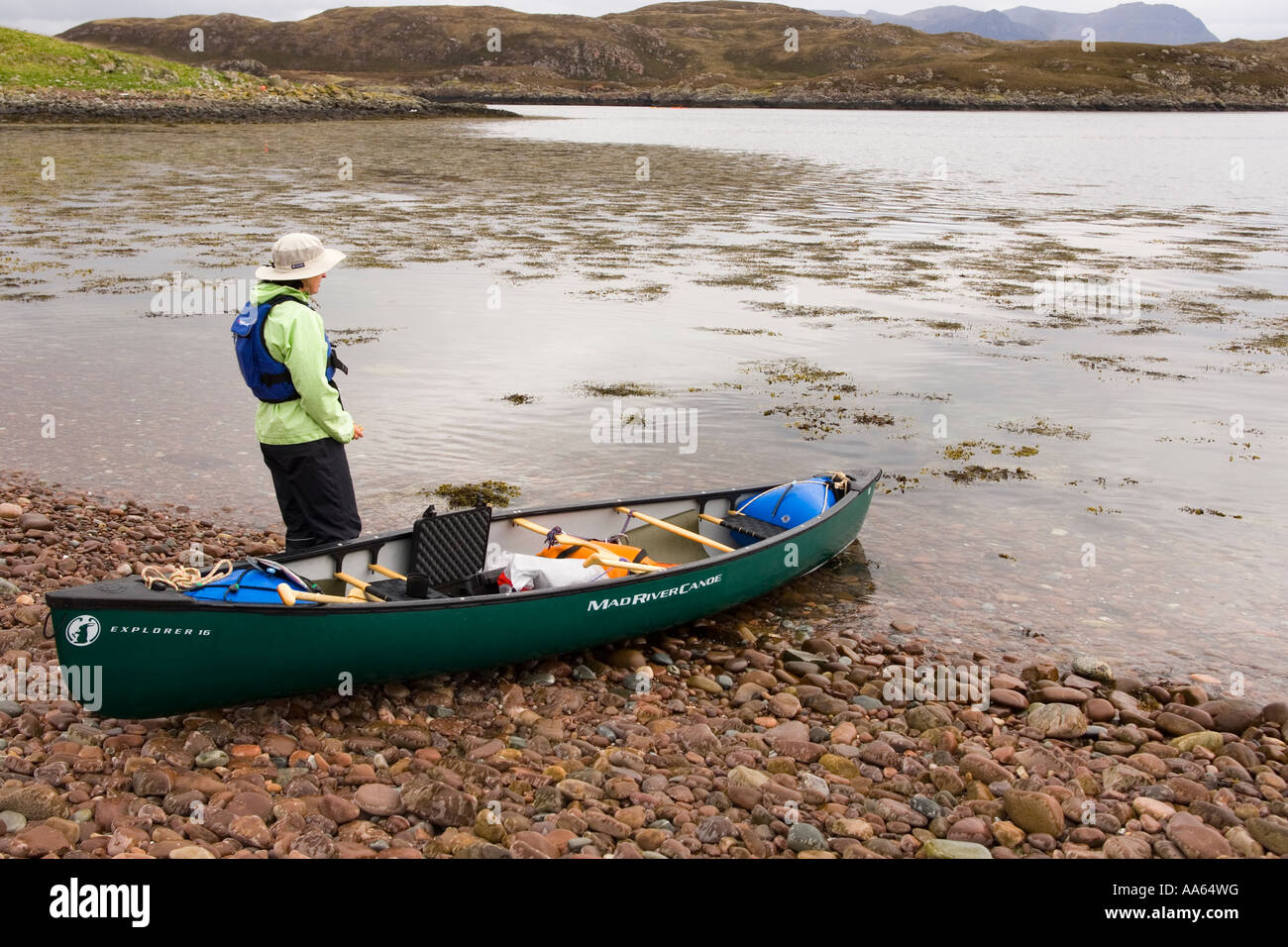 A female canoeist and canoe on a beach on the Summer Isles Scotland May ...