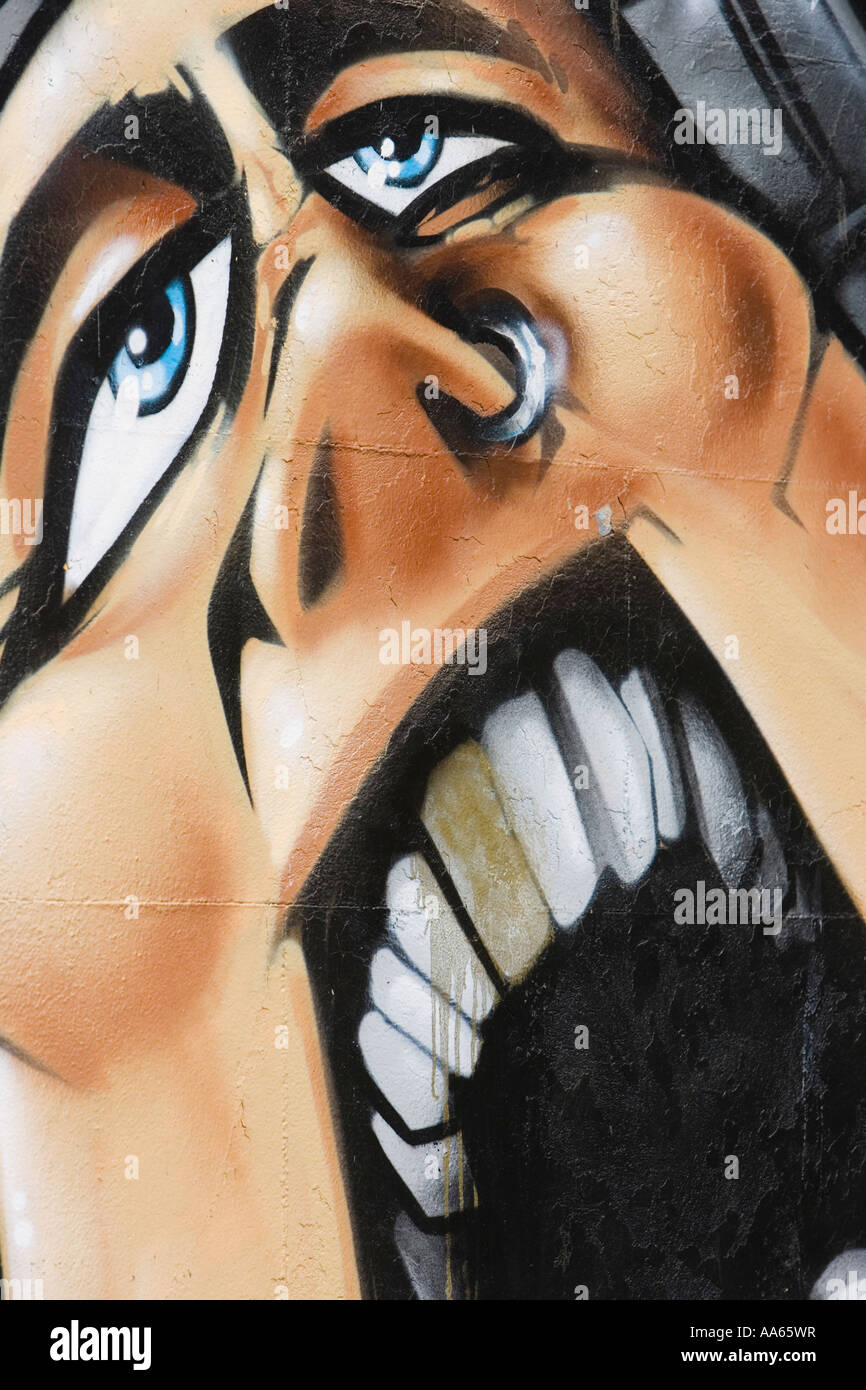 Urban graffiti art of a mans face spray painted on the end of a house ...