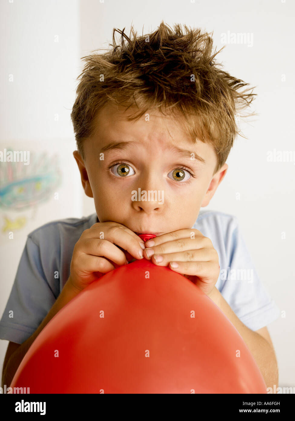 boy 7 blowing up a red balloon for a birthday party looking wide eyed ...
