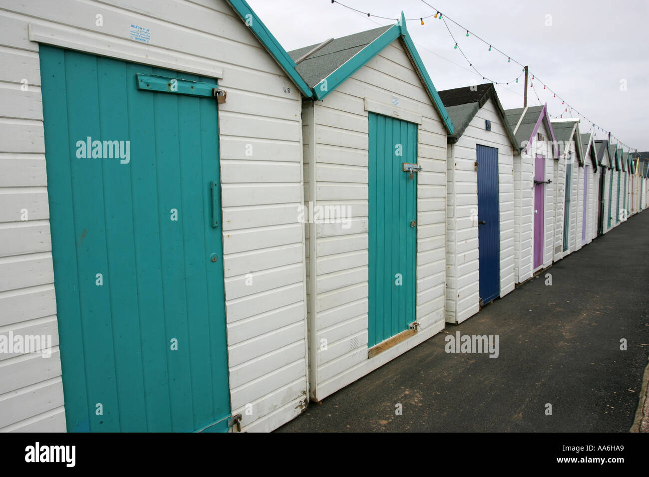 Long row line of white Victorian beach huts with brightly painted doors ...