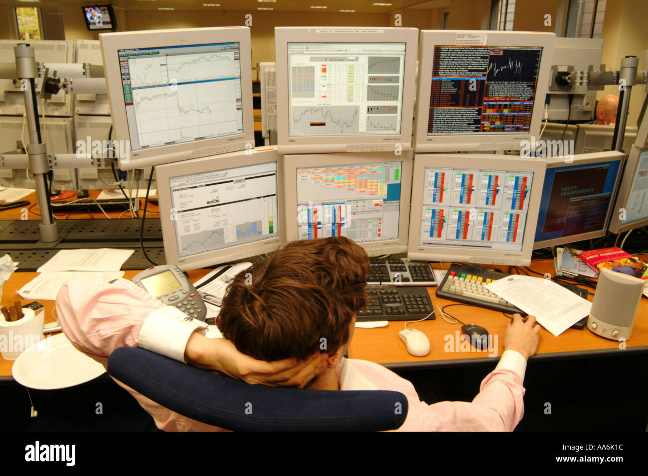 A city dealer sitting casually at his desk looking at the information ...