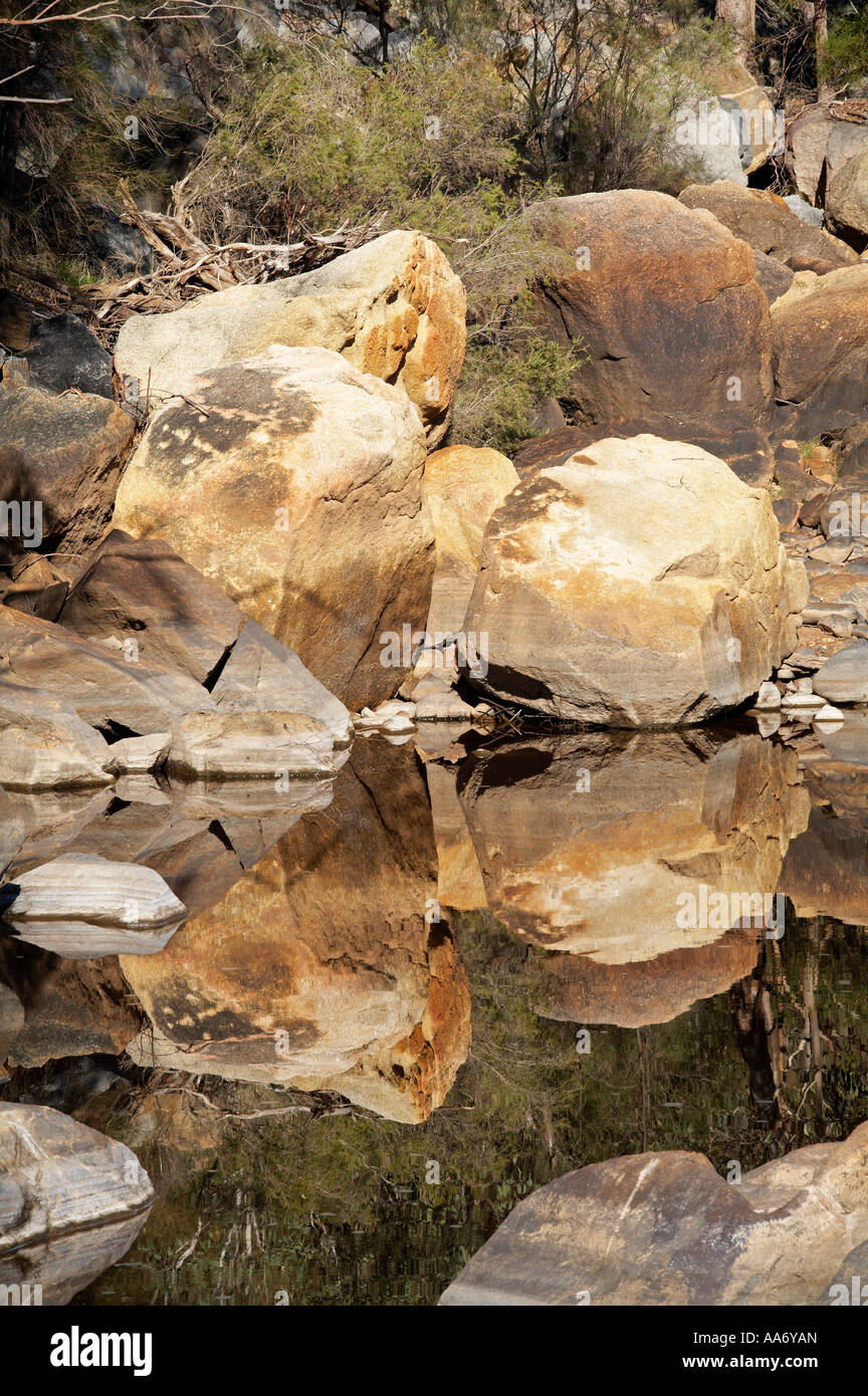 Ancient giant granite boulders reflected in the calm waters of a ...